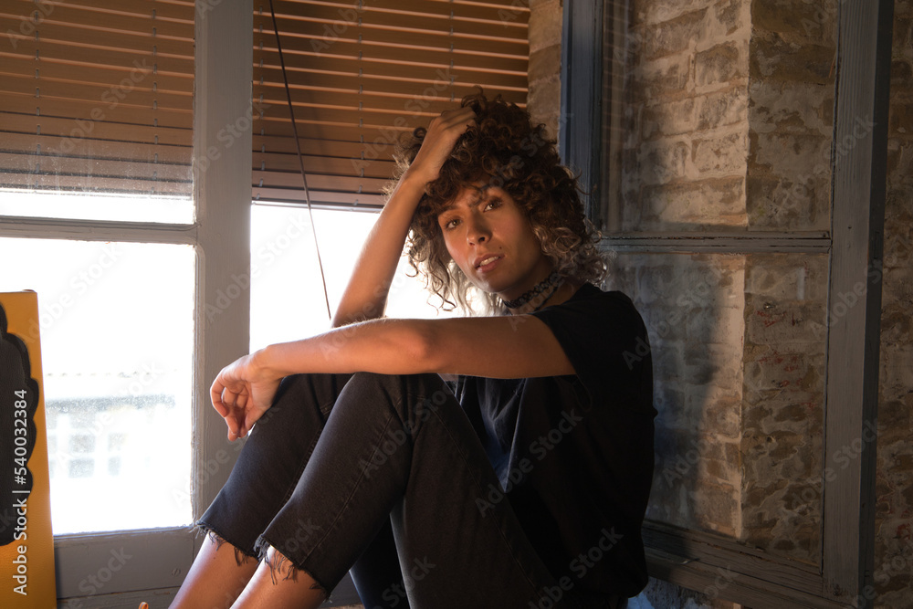 Beautiful woman sitting on the edge of a large window in her studio ...