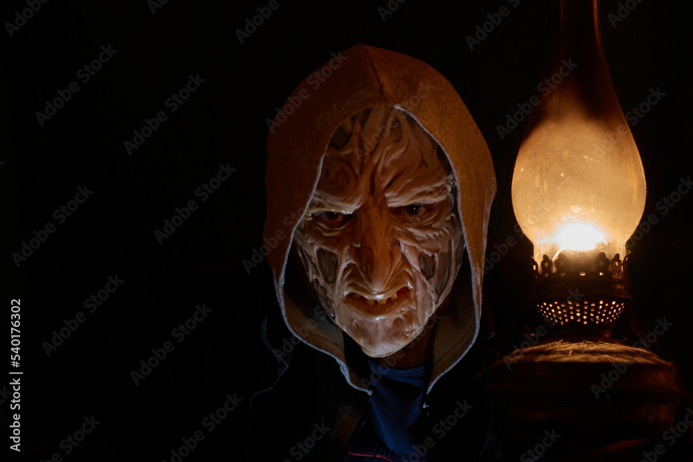 Stock-Foto „A man in a hood and mask of a Halloween monster sits and ...