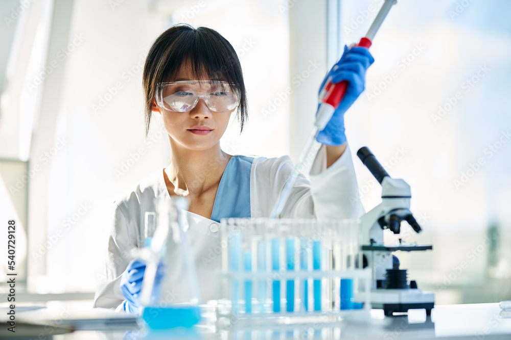 Female scientist making microbiology research using pipette, flask and ...