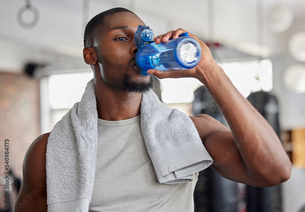 Water, drink and fitness with a sports man in a gym for exercise while ...