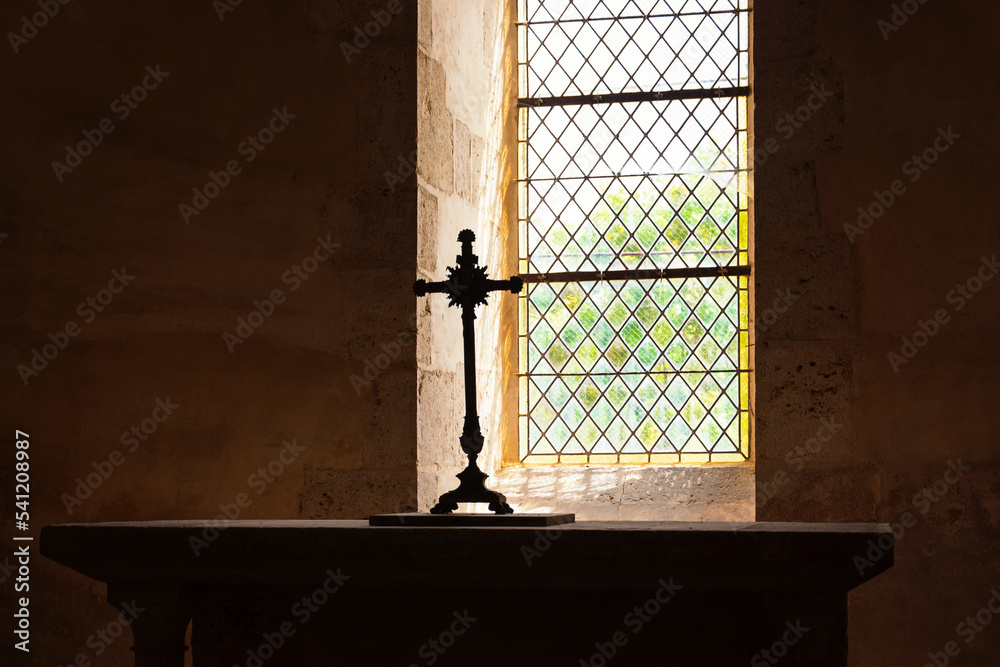 Cross silhouette on altar near window in dark empty old chapel. Game of ...