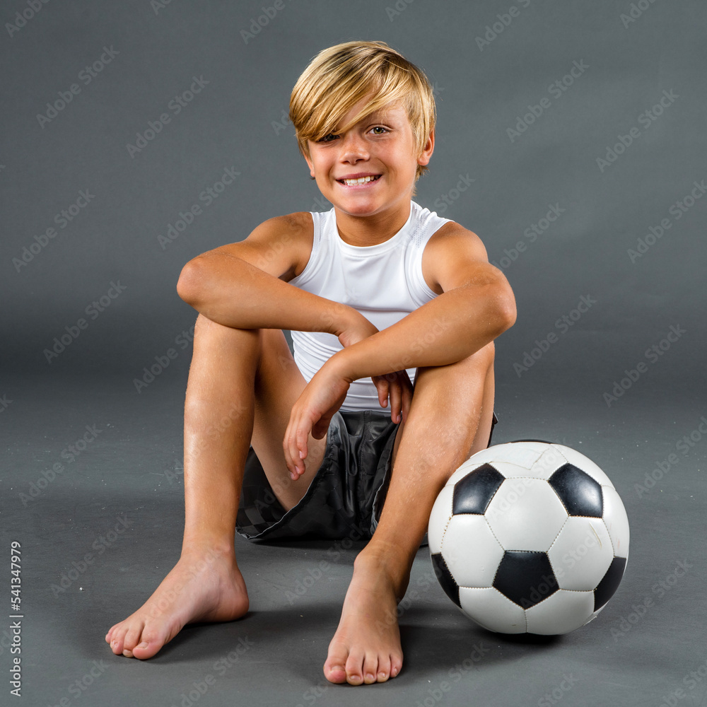 Happy young soccer player sitting barefoot on the ground with his soccer ball Stock Photo ...