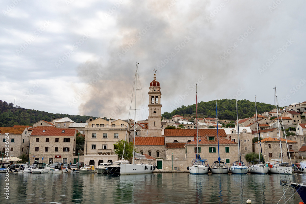 Brown, wildfire smoke rising above the town of Pucisca on Brac island ...