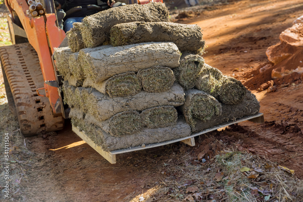 Boom truck unloading green grass turf rolls in pallets for landscaping ...