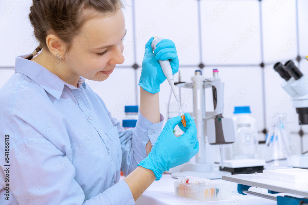 young woman laboratory assistant loads biological sample into micro ...
