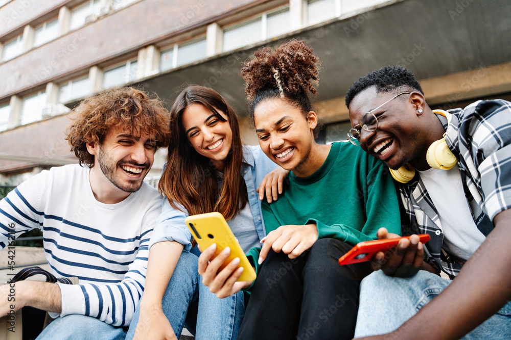 Group of university student friends sitting together using mobile phones to share content on ...