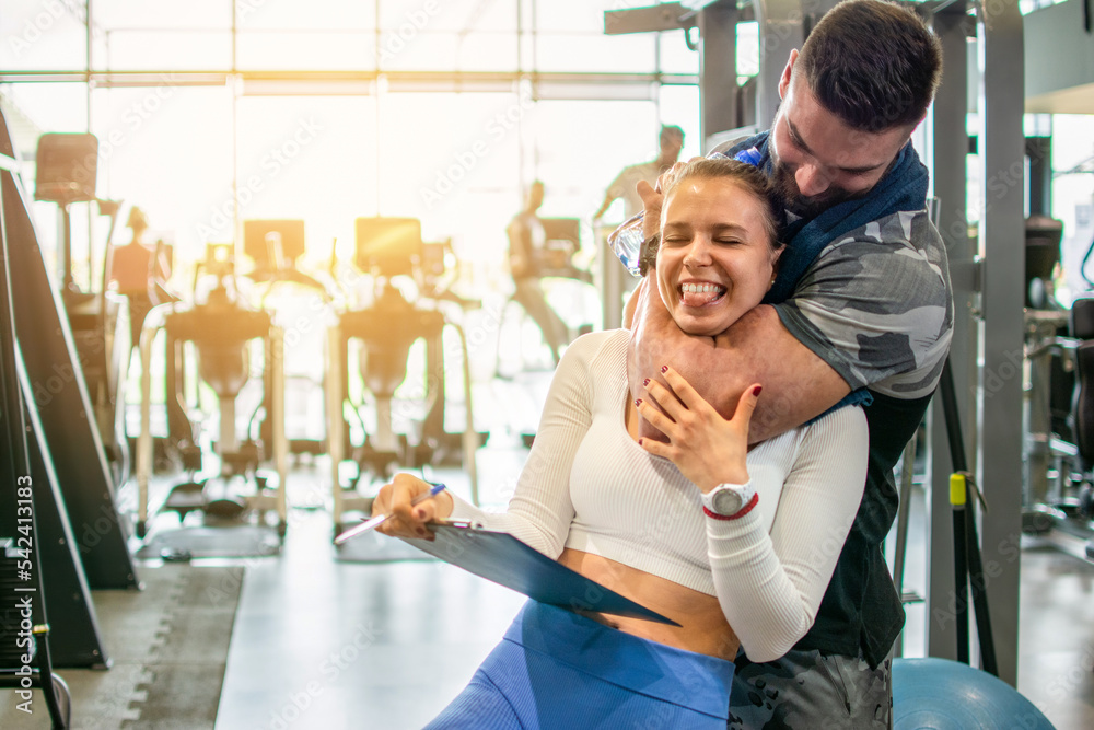 Muscular fit man choking a young female personal trainer with his arm ...