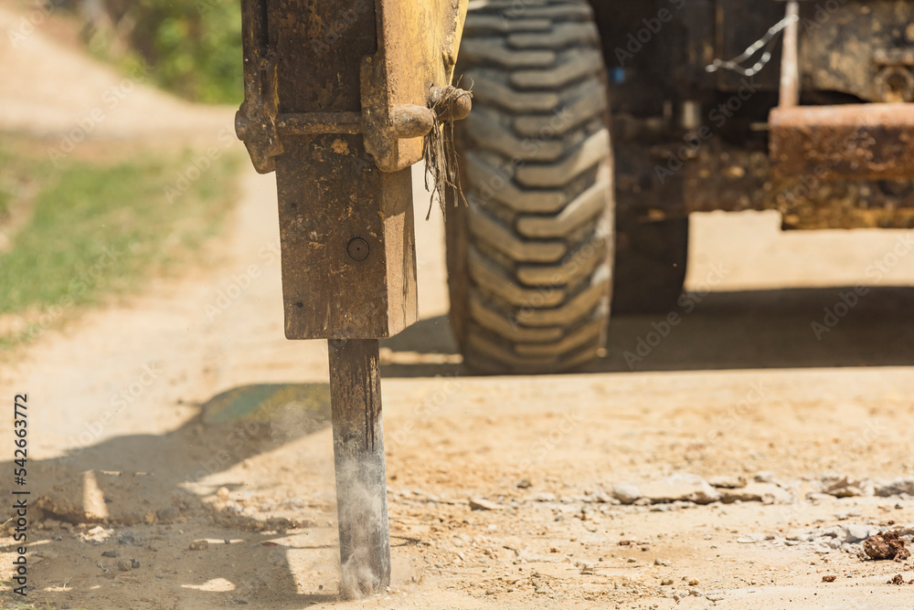 An excavator fitted with a hydraulic breaker destroying a portion of a ...