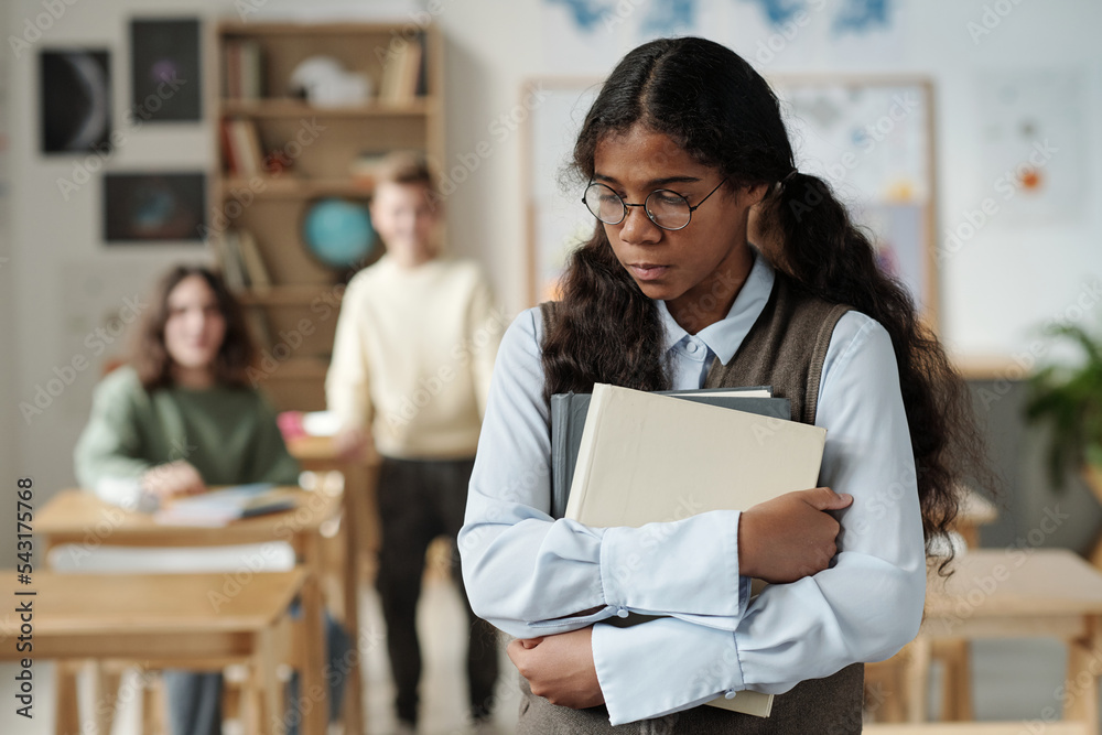 Offended secondary school pupil with books standing in front of camera ...