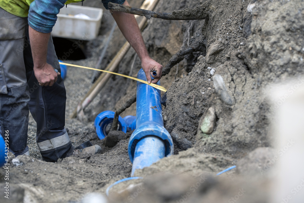 Workers install underground pipes for water, sewerage, electricity and ...