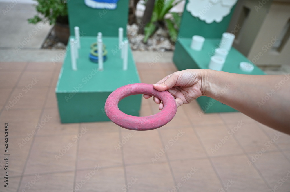 Hand holding a red rubber ring for throwing rings in throwing rings ...