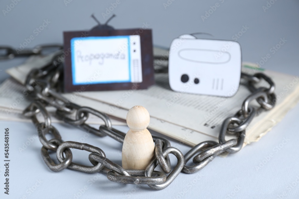 Propaganda concept. Human mired in media field. Chained wooden figure ...