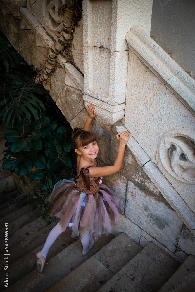 Niña pequeña bailando ballet en un jardín con muros románicos de piedra ...