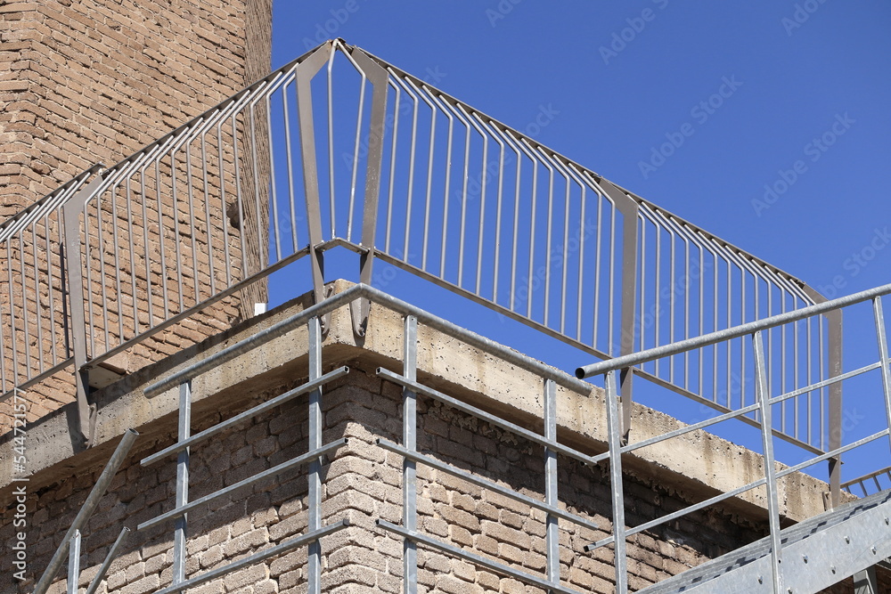 A steel railing installed on the terrace of a gray brick building ...