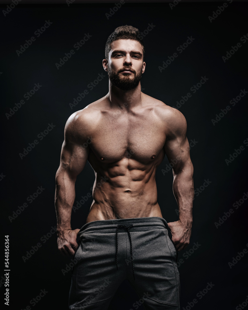 Slim muscular male model at black background. Fitness shirtless guy in ...