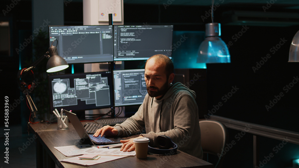 Software engineer typing source code on multiple monitors, displaying terminal window with html ...
