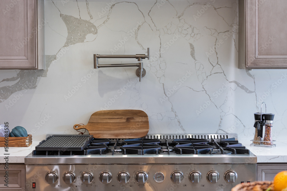 Modern kitchen details of large gas stove with pot filler, wood cutting ...