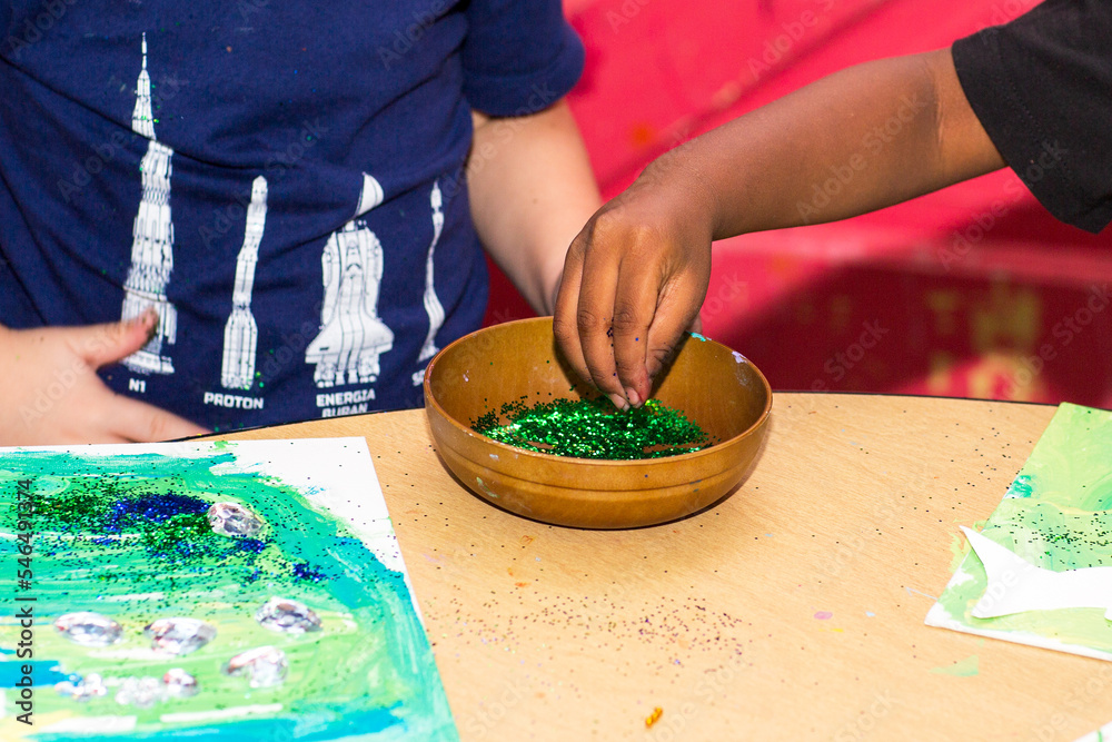 Two kids works together in a preschool class. Kids hands are during ...
