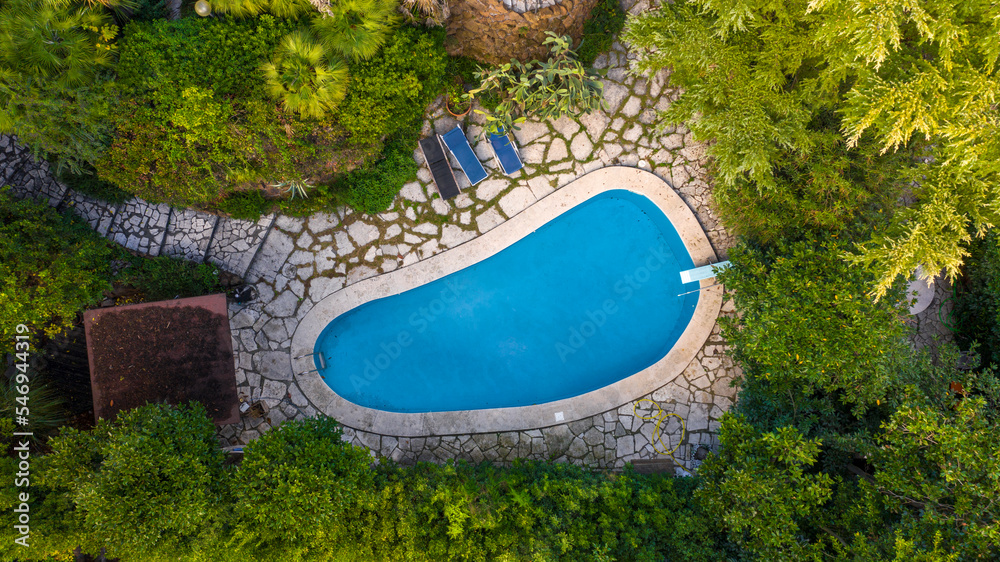 Aerial view of a swimming pool with wavy and curved shapes. Around the ...