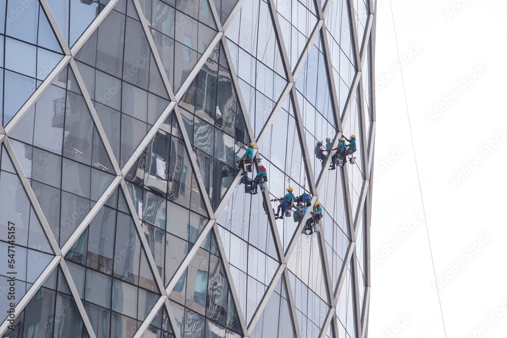 Workers peeling film off glass that has just been installed on a ...