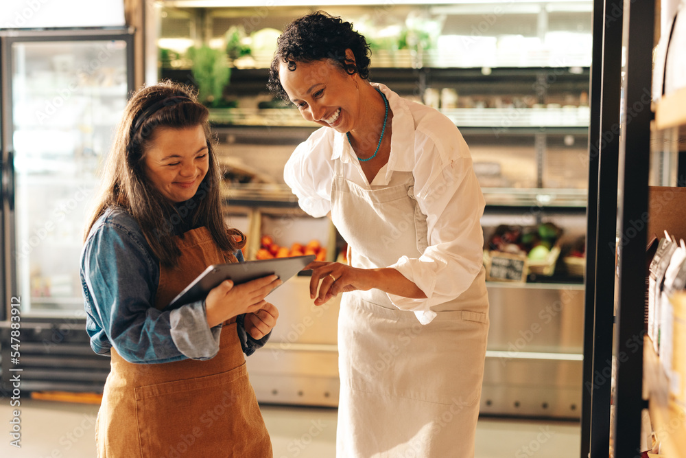 Convenience store workers using a digital tablet together Stock Photo ...