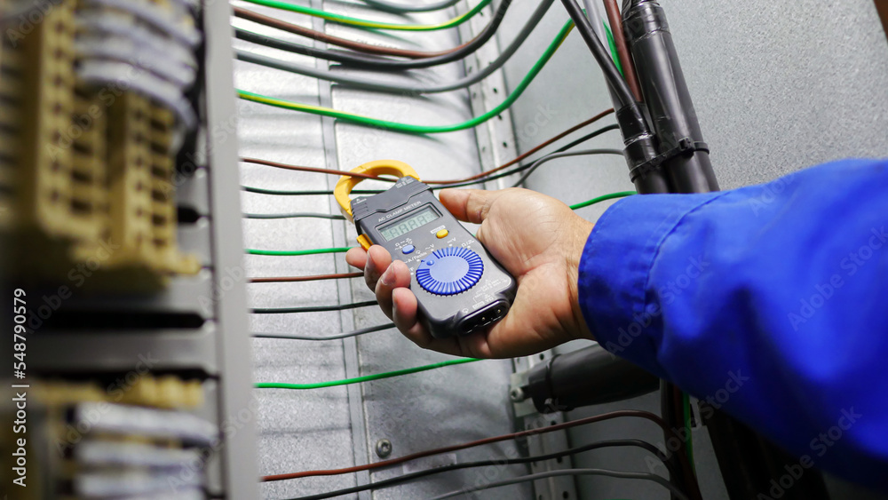 Hand closeup of electrical engineer to use digital ampere meter to ...