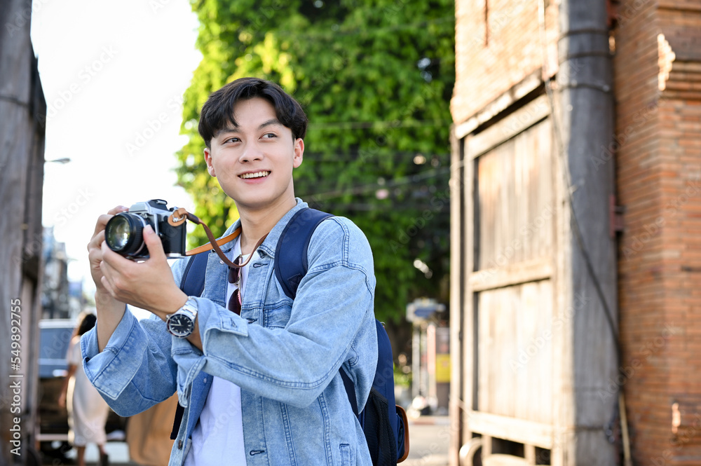 Asian male traveler or tourist taking a picture by his retro camera ...