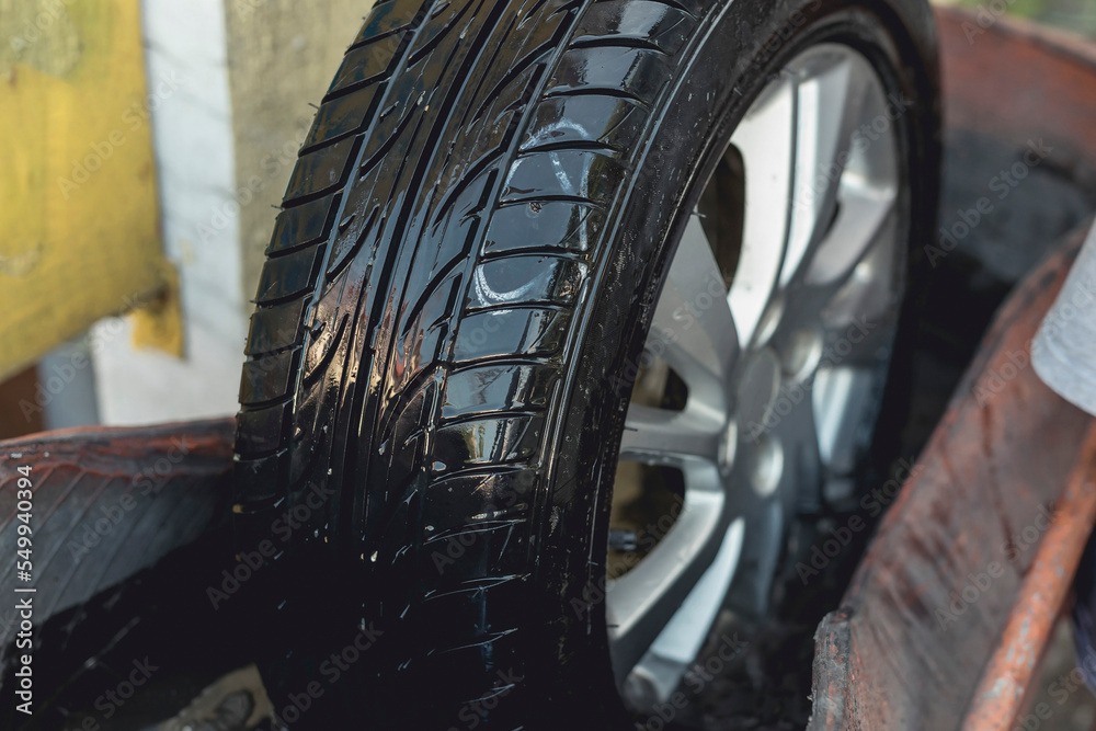 Submerging a tire in a soap and water solution to check for leaks or ...