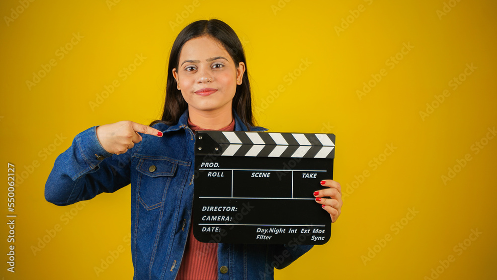 Beautiful young Asian Indian woman standing holding clapperboard ...