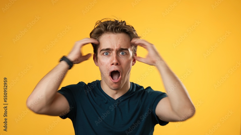 Handsome thinking young man 20s, looks at camera gives mind blown ...