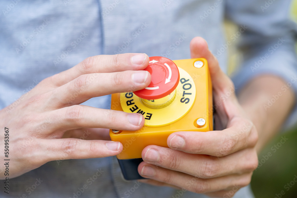 Stock-Foto „Anonymous man pressing an emergency stop industrial safety ...