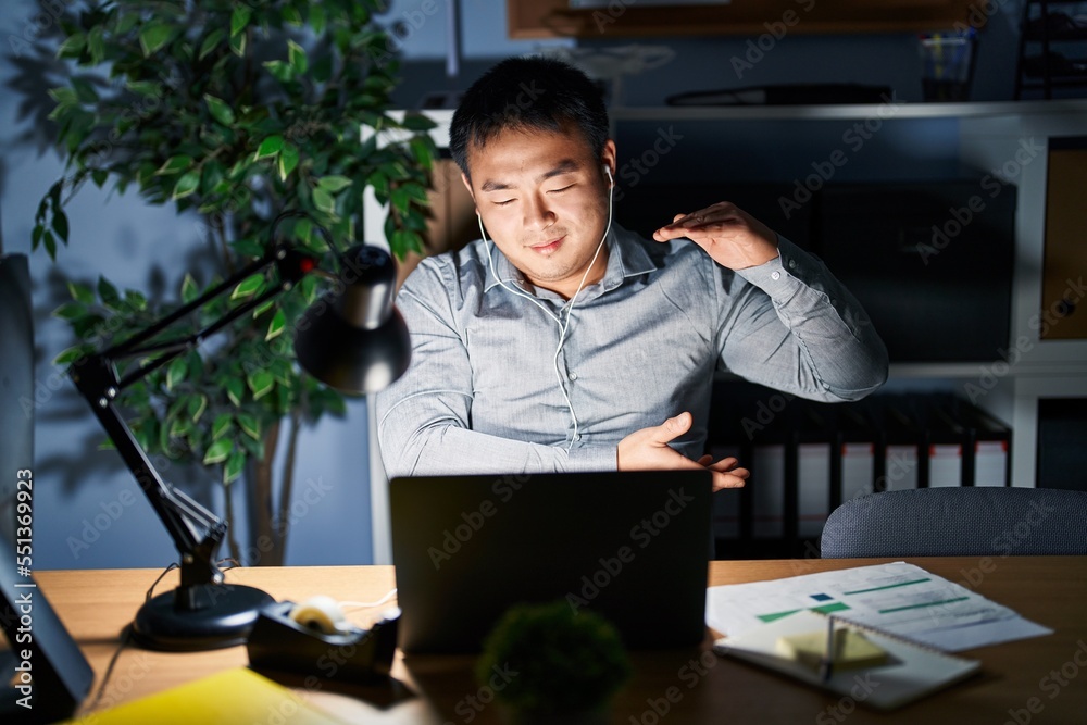 Young chinese man working using computer laptop at night gesturing with ...