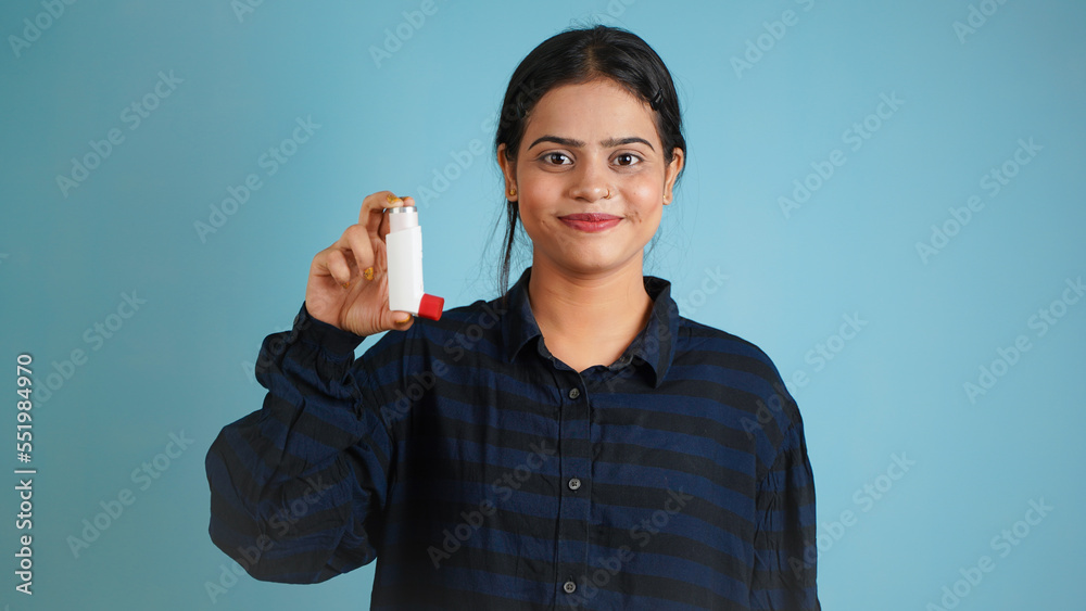 Portrait of a cheerful young woman holding asthma inhaler, Asian Indian ...