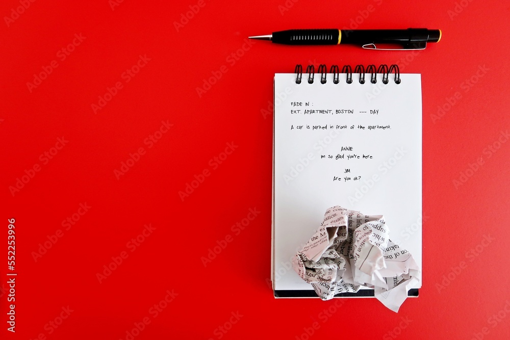 Pen , crumpled paper and notebook with screenwriting scene written, on ...