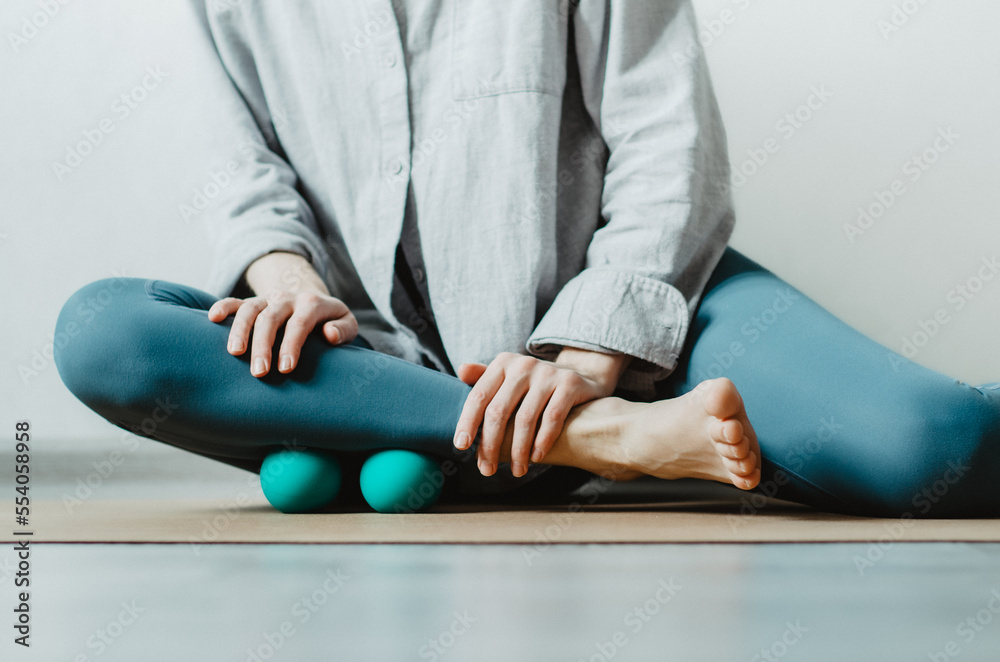 Woman doing self myofascial release on shin muscles with two therapy ...