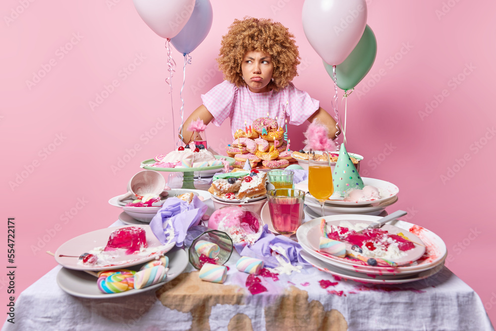 Photo Stock Unhappy gloomy young woman poses near messy table after ...