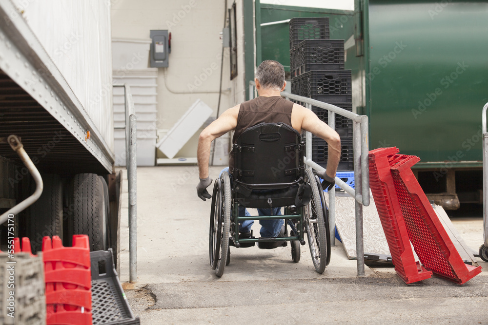 Loading dock worker with spinal cord injury in a wheelchair going up ...