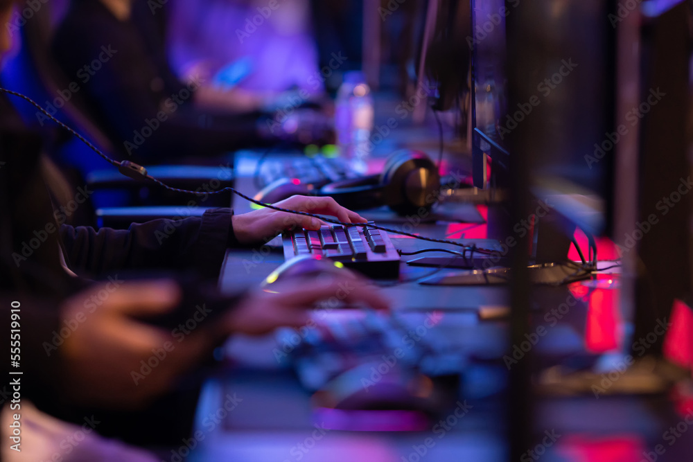 Young men sit at computer gaming setups and playing an online game ...