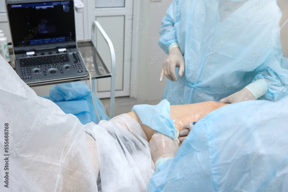 Patient on operating table is covered with medical sheets, surgeon is ...