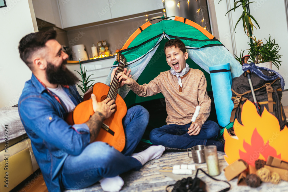 Dad with his son camp inside their home. They have pitched a tent and ...