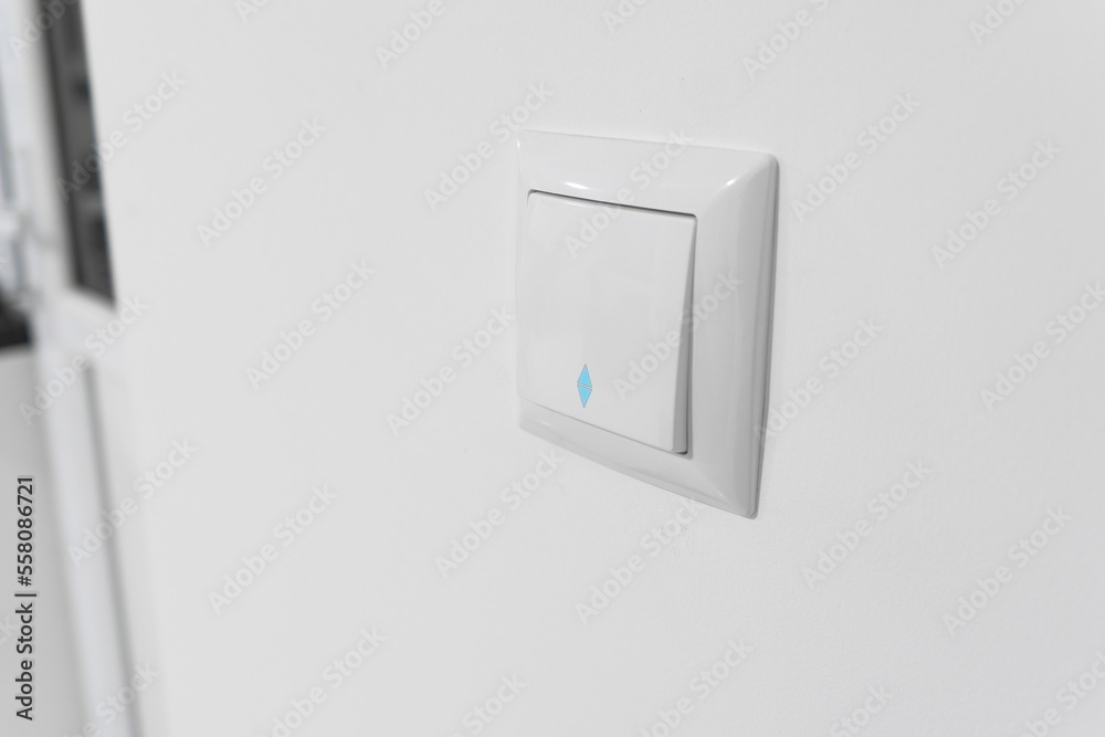 Light switch. White plastic mechanical switch installed on a white wall ...