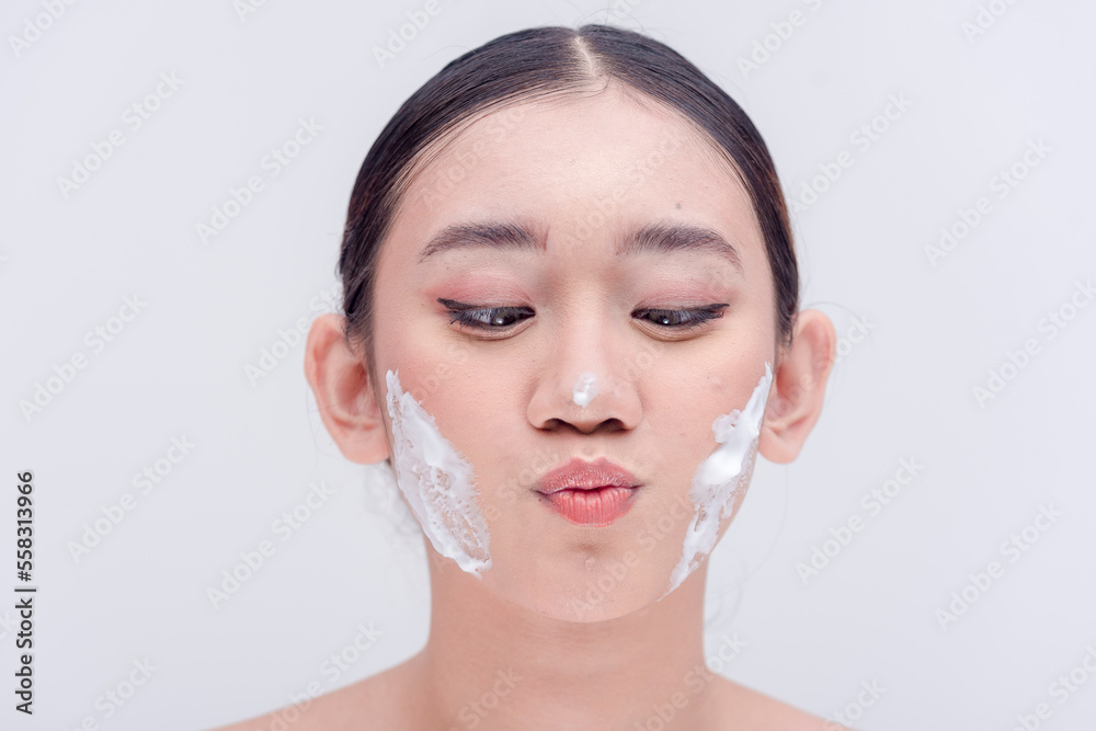 A playful young girl pouting her lips and looking at her nose while ...
