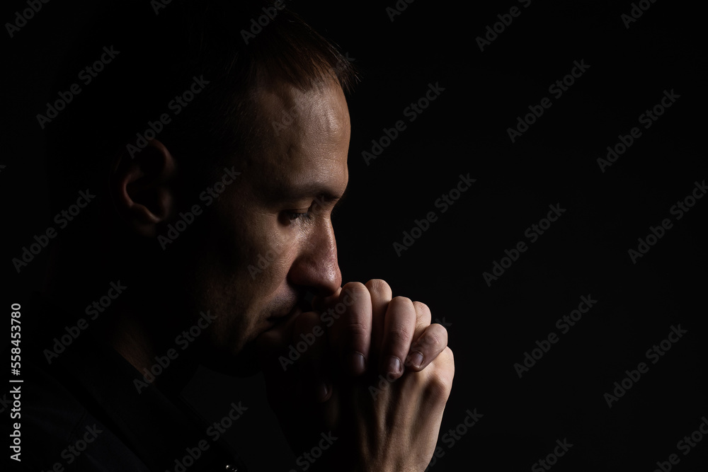 Close up of faithful mature man praying, hands folded in worship to god ...