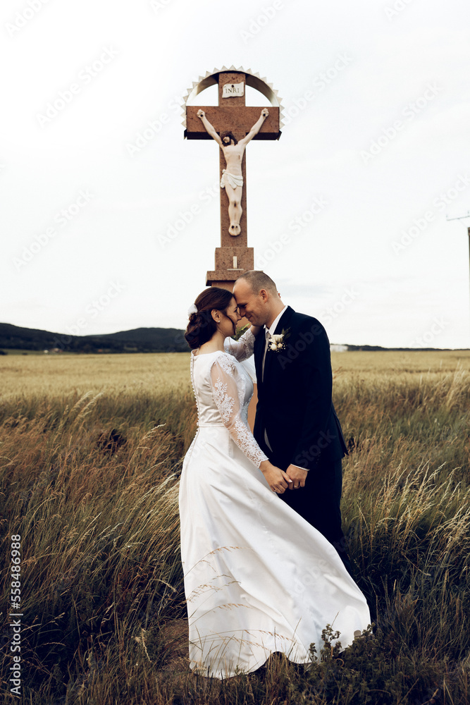 bride and groom holding hands in front of jesus christ statue during ...