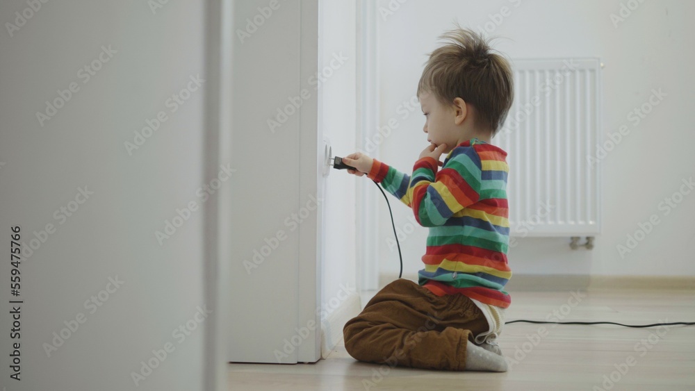 Little child connecting the electrical device plugging it into the wall ...