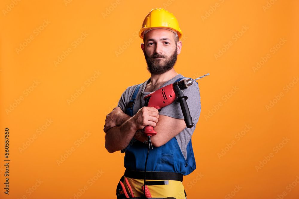 Happy building contractor holding power drill gun and posing in studio ...
