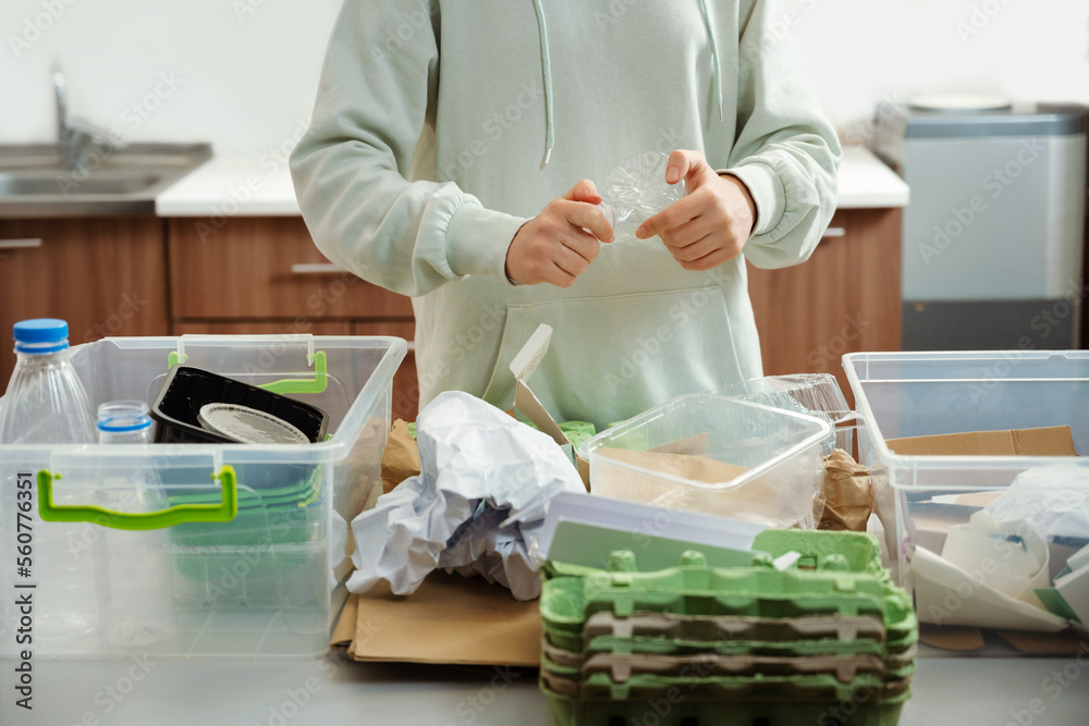 Fotografie Sorting garbage for recycling. Teen girl squeezes a plastic ...