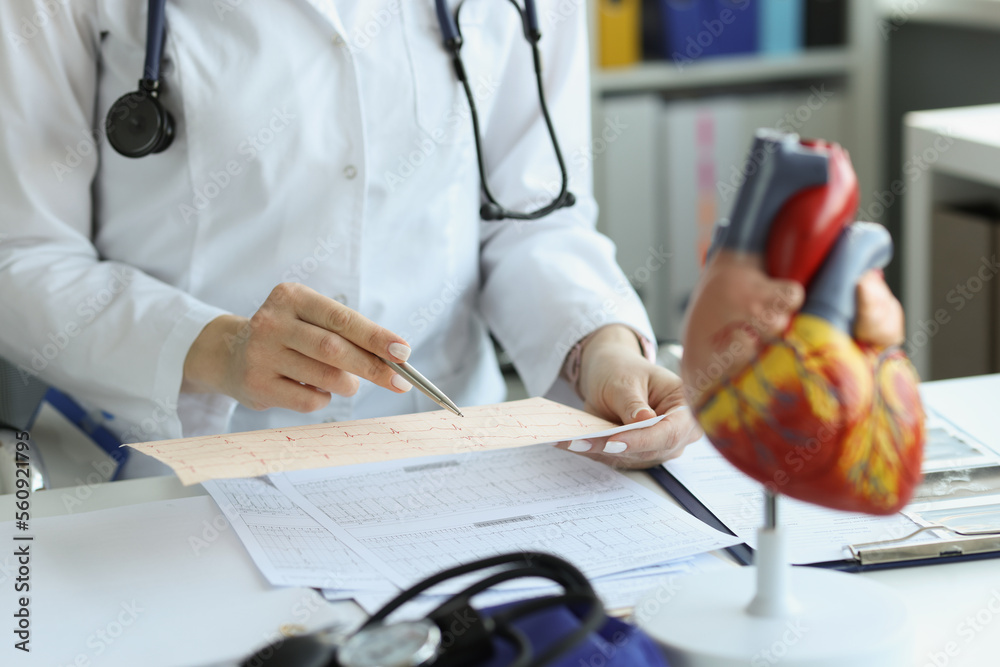 Cardiologist doctor holding and reading an ecg paper report of patient ...
