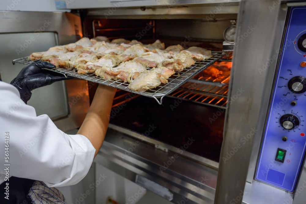 Chef in white coat prepares fresh chicken in big oven. Baked chicken ...