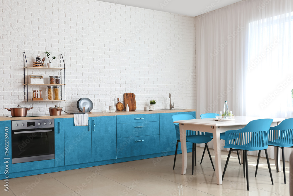 Light interior of modern kitchen with blue counters and dining table ...